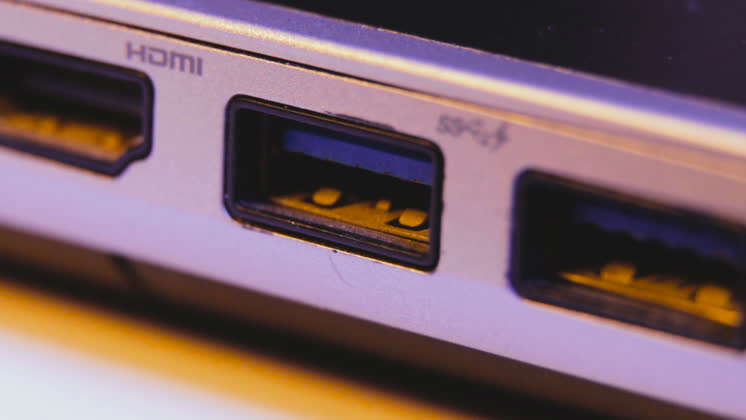 Closeup of USB flash drive inserted into port on the side of a laptop ...